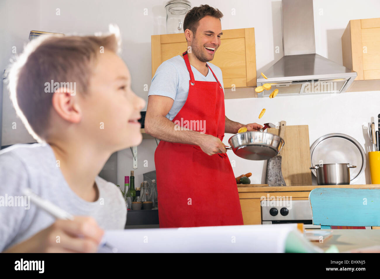 Father preparing food while his son doing his homework Stock Photo - Alamy