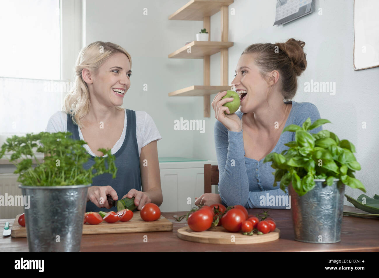 Two young women talking kitchen preparing salad Stock Photo - Alamy