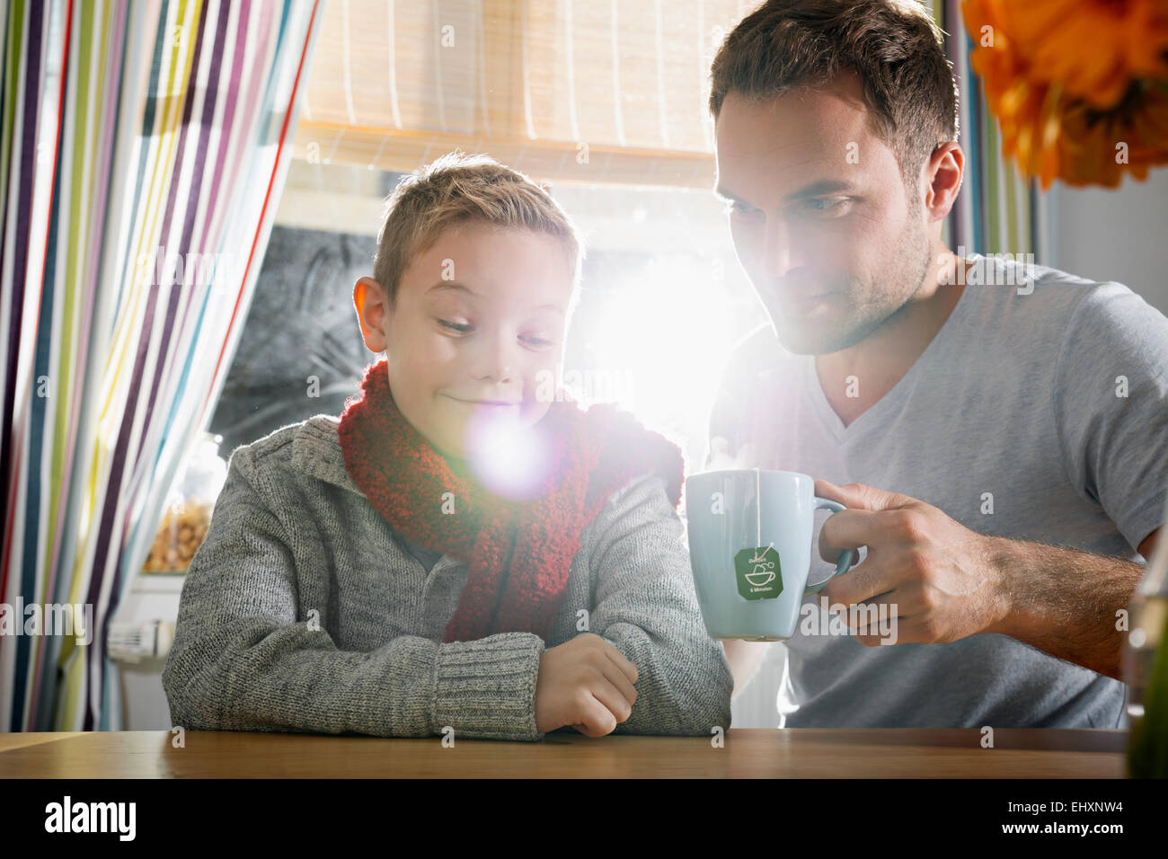 Boy having a cold sitting in the kitchen with his father Stock Photo ...
