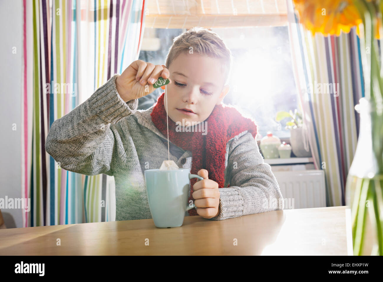 Boy having a cold sitting in the kitchen with cup of tea Stock Photo ...