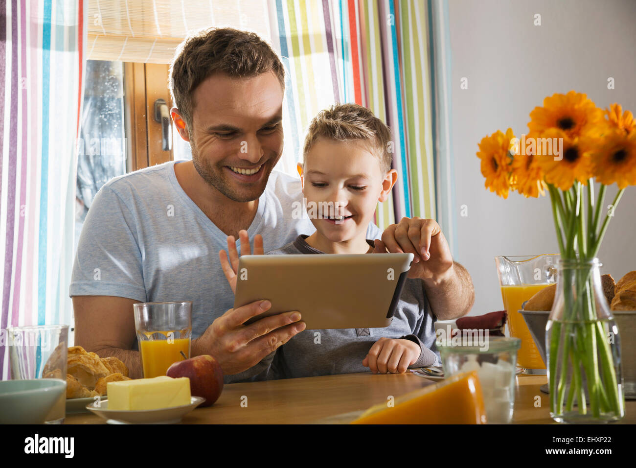 Father and son sitting at breakfast table using digital tablet Stock ...