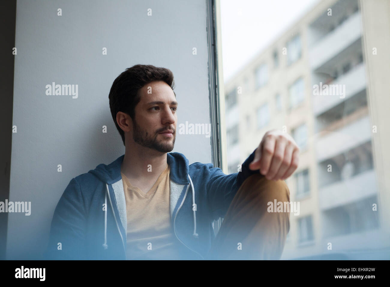 Portrait of man looking through window Stock Photo - Alamy