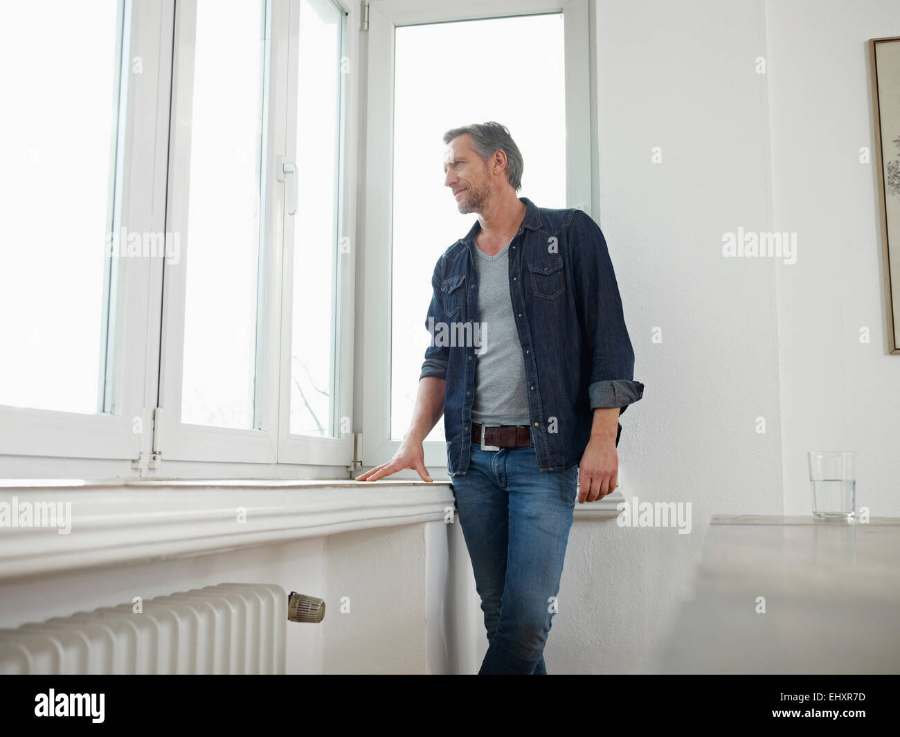 Germany, Cologne, Mature man standing at window, looking out Stock ...