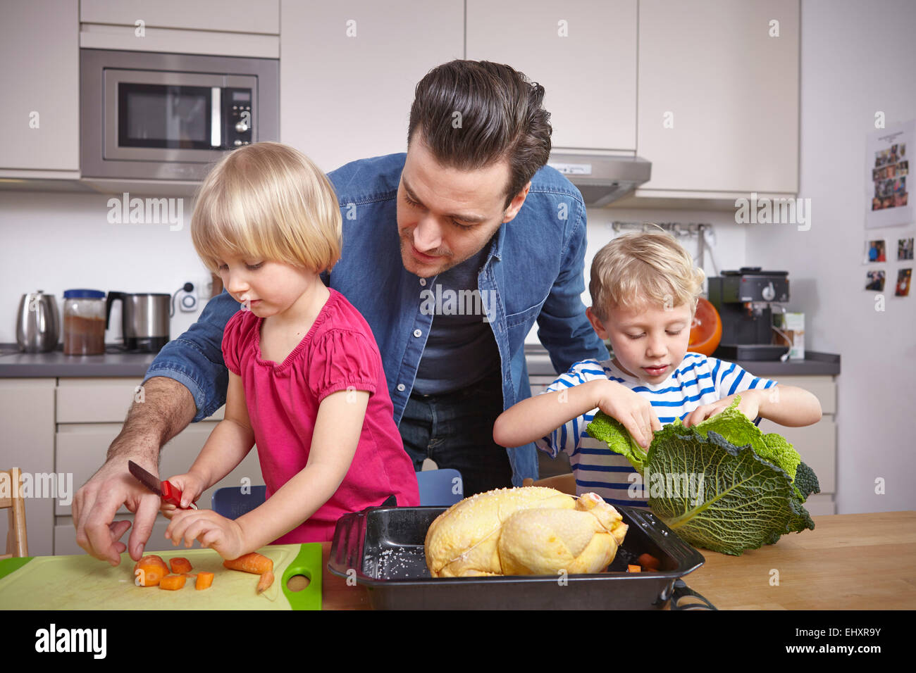 Father preparing food in kitchen with children Stock Photo - Alamy
