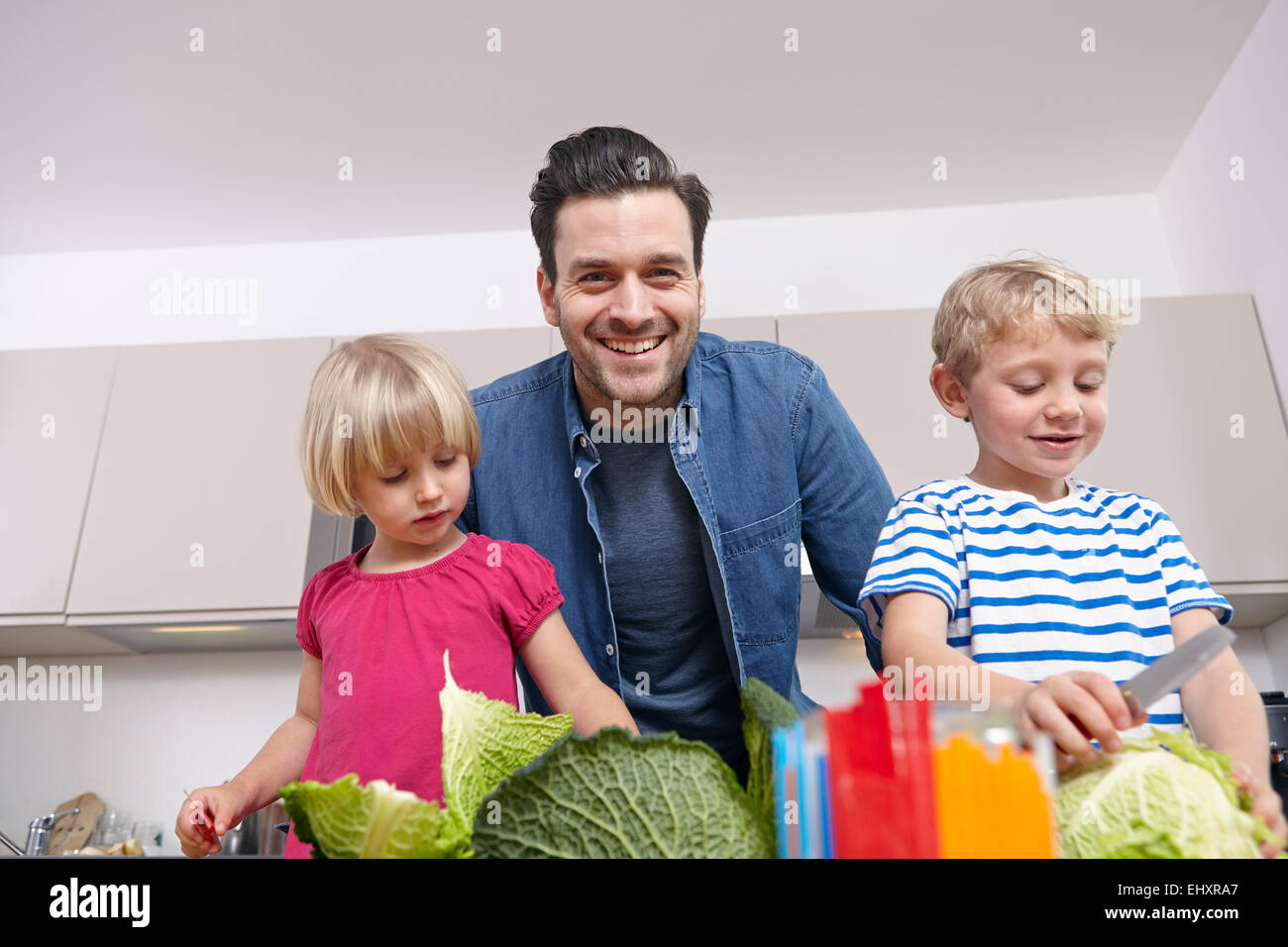 Father preparing food in kitchen with children Stock Photo - Alamy