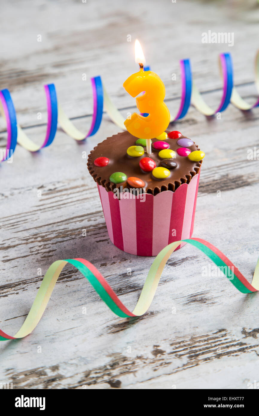 Birthday muffin with chocolate buttons and lighted candle Stock Photo ...