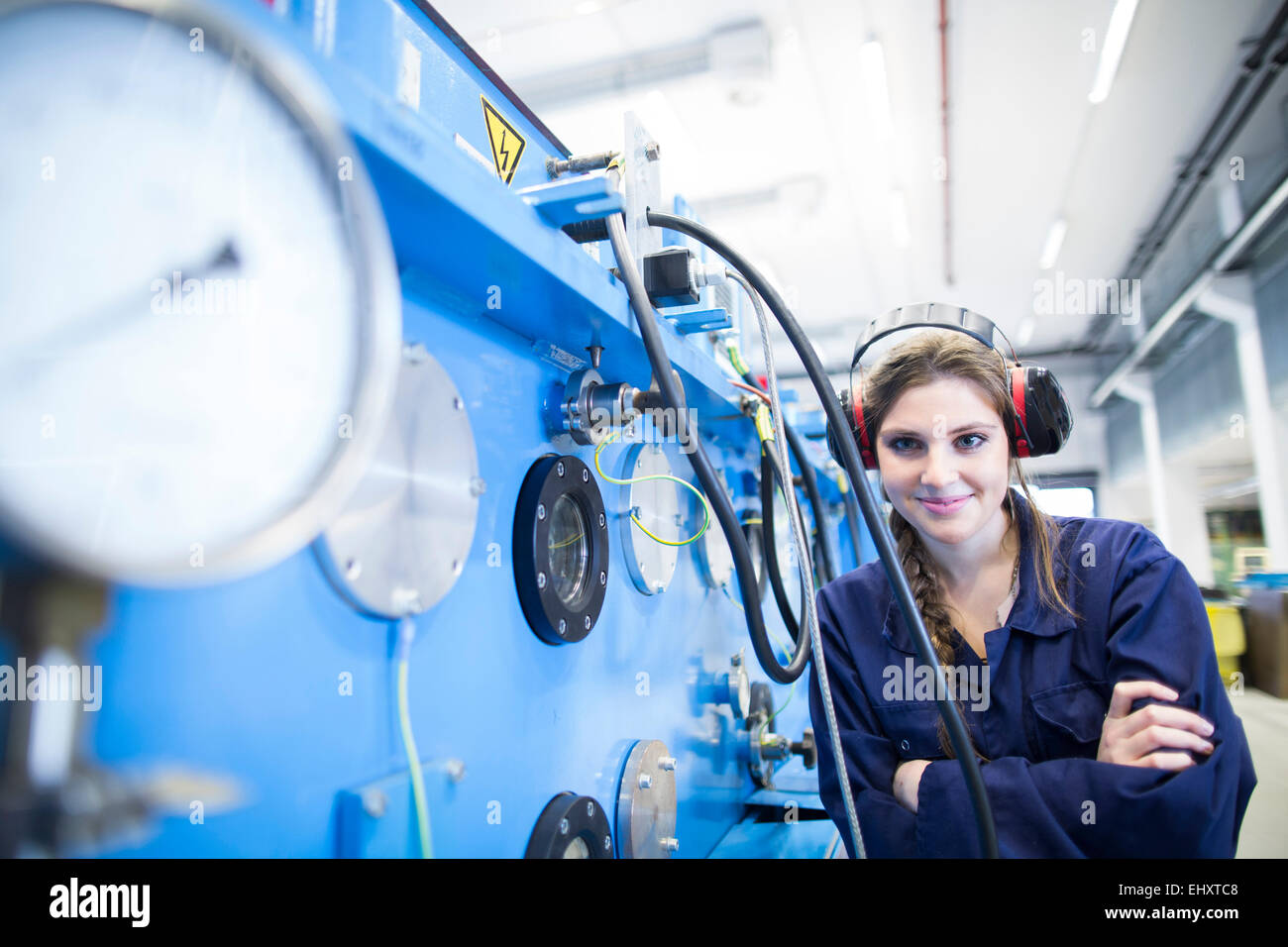 Smiling technician in factory hall leaning against machine Stock Photo ...