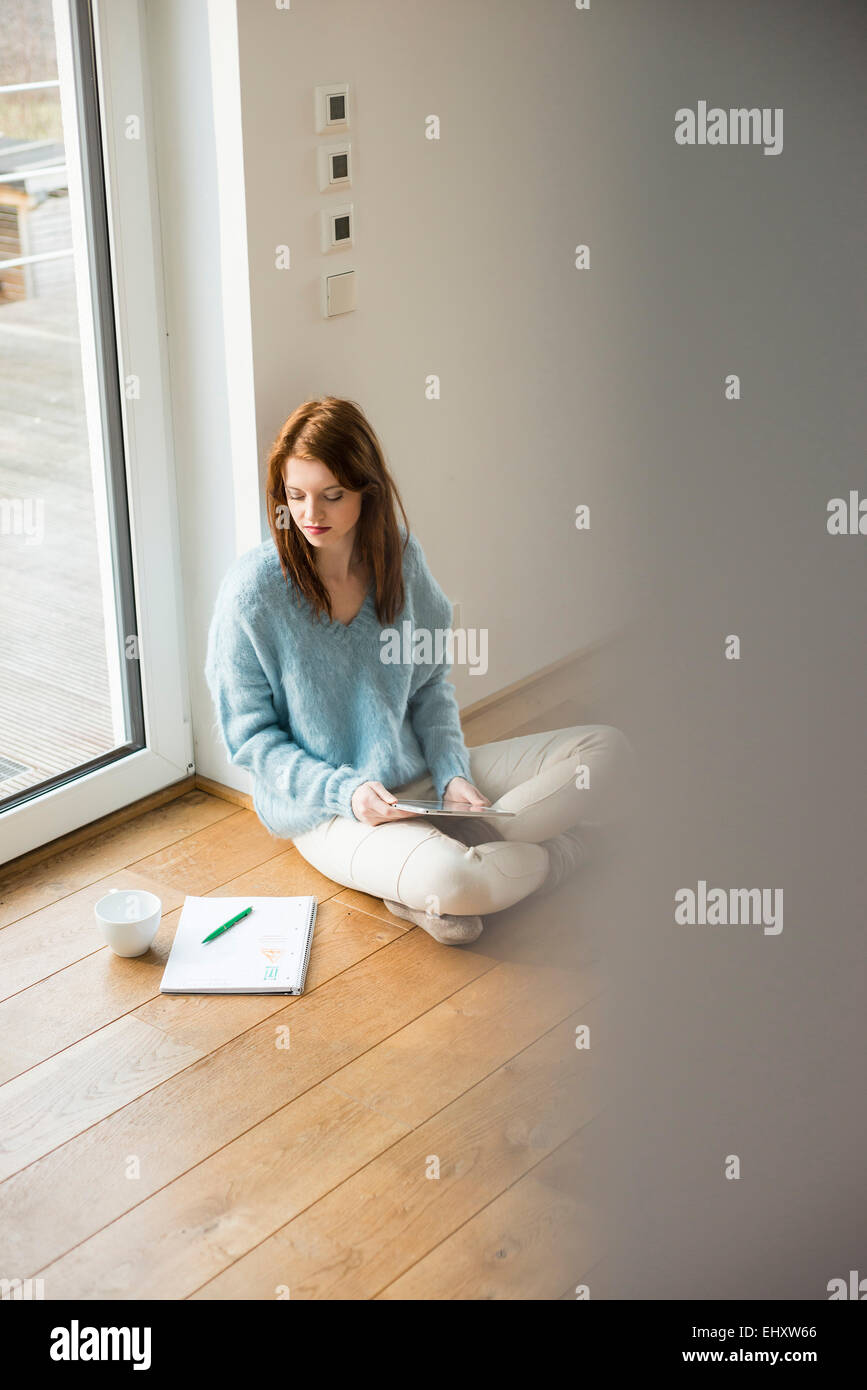 Young woman sitting on floor taking notes Stock Photo - Alamy