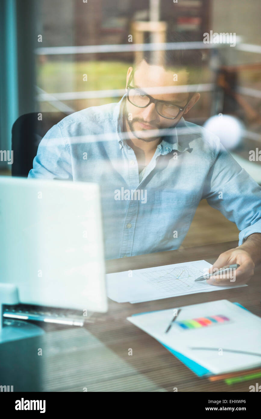Young man behind windowpane working at computer Stock Photo - Alamy