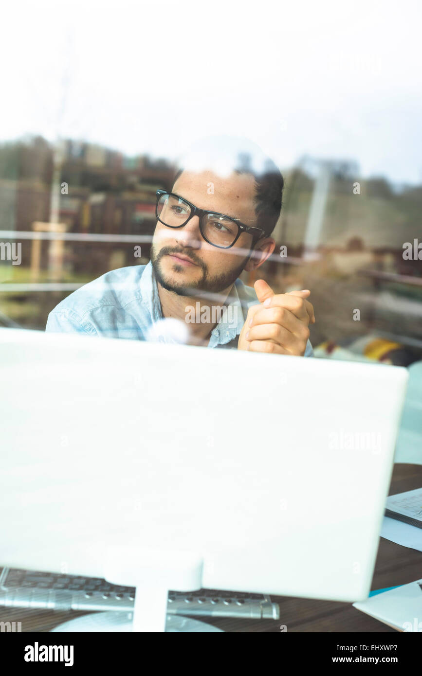 Young man behind windowpane working at computer Stock Photo - Alamy