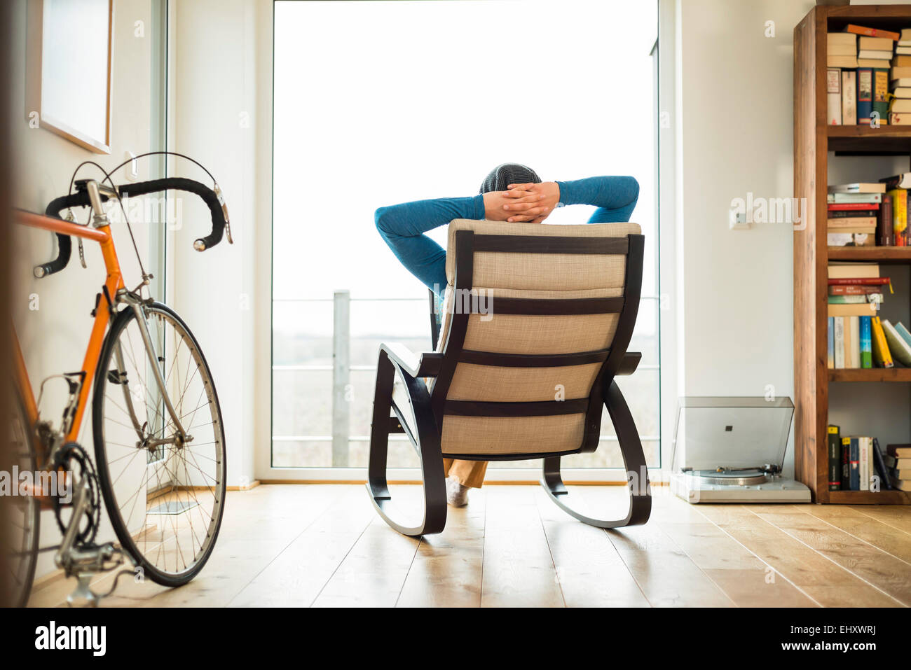 Man sitting on rocking chair looking out of window Stock Photo - Alamy