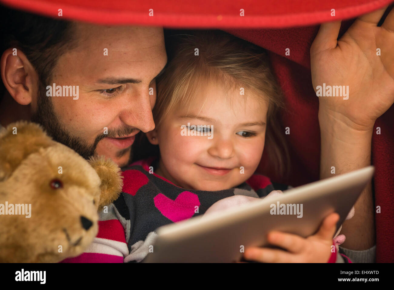 Father and daughter with digital tablet under blanket Stock Photo - Alamy