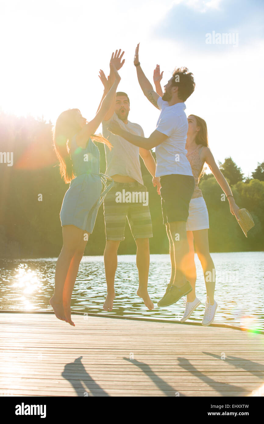 Four friends high fiving at a lake in backlight Stock Photo - Alamy