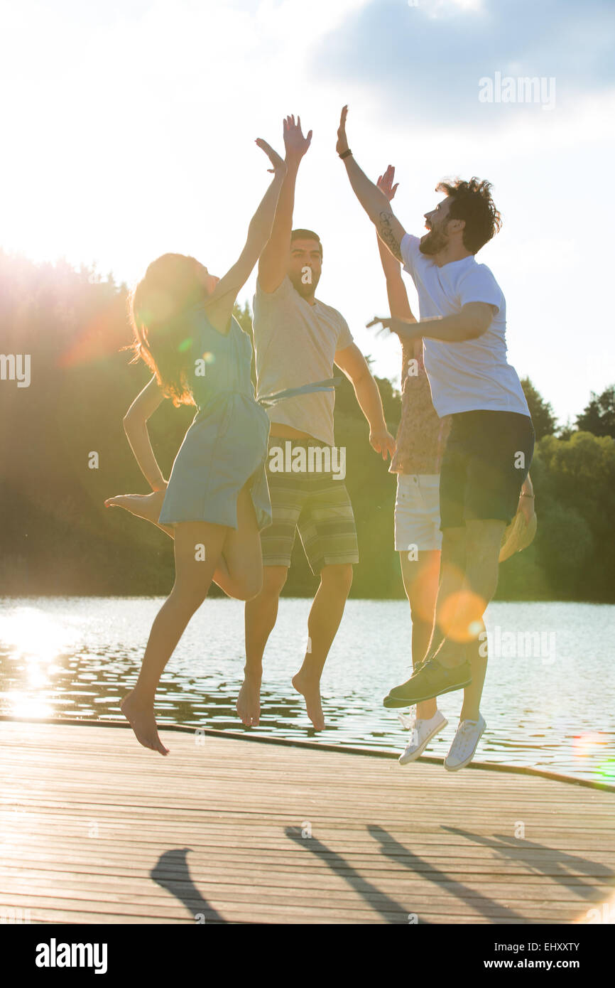 Four friends high fiving at a lake in backlight Stock Photo - Alamy