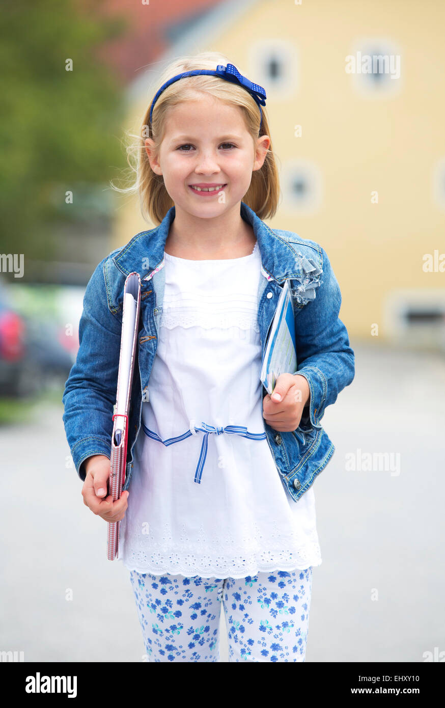 Portrait of smiling little girl with file and exercise book Stock Photo ...