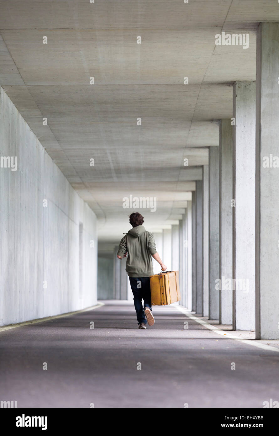 Man with leather suitcase running in a car park Stock Photo - Alamy