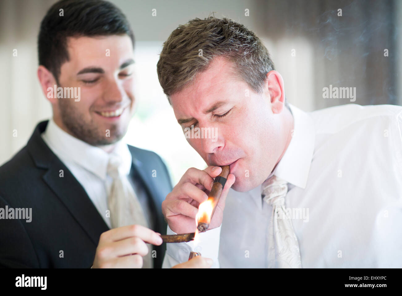 Groom smoking a cigar with best man before wedding Stock Photo - Alamy