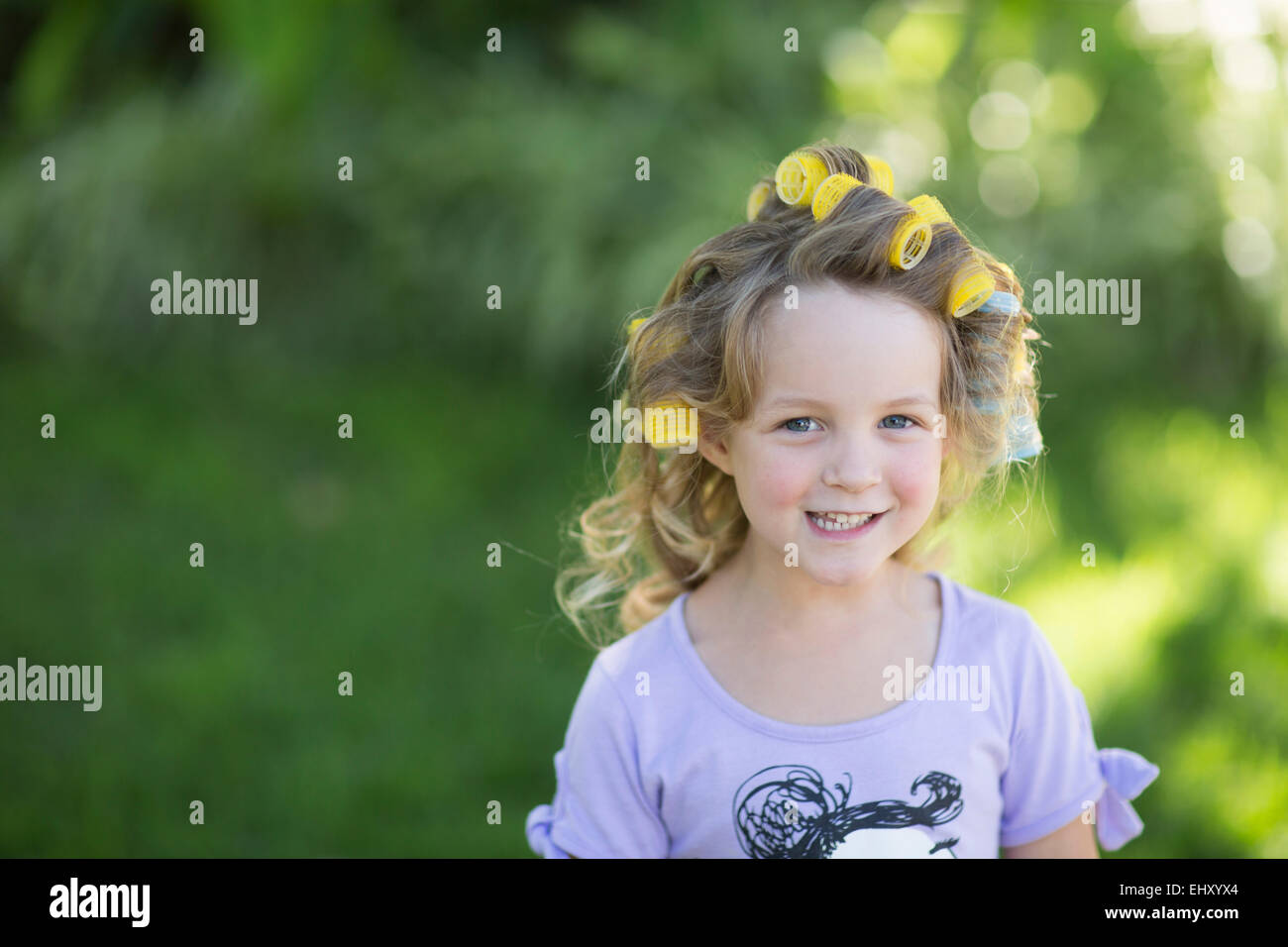 Smiling flower girl with curlers in her hair Stock Photo - Alamy