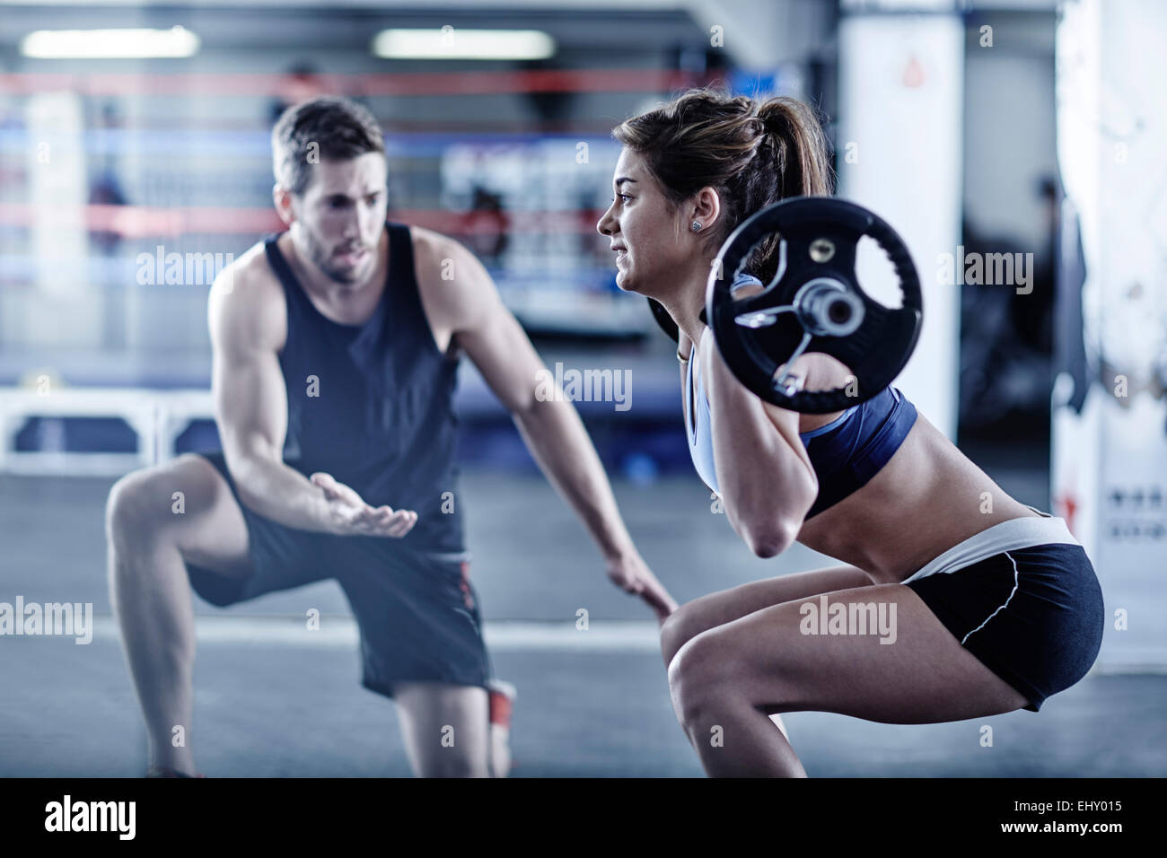 Trainer watching woman doing fitness training with weights Stock Photo ...