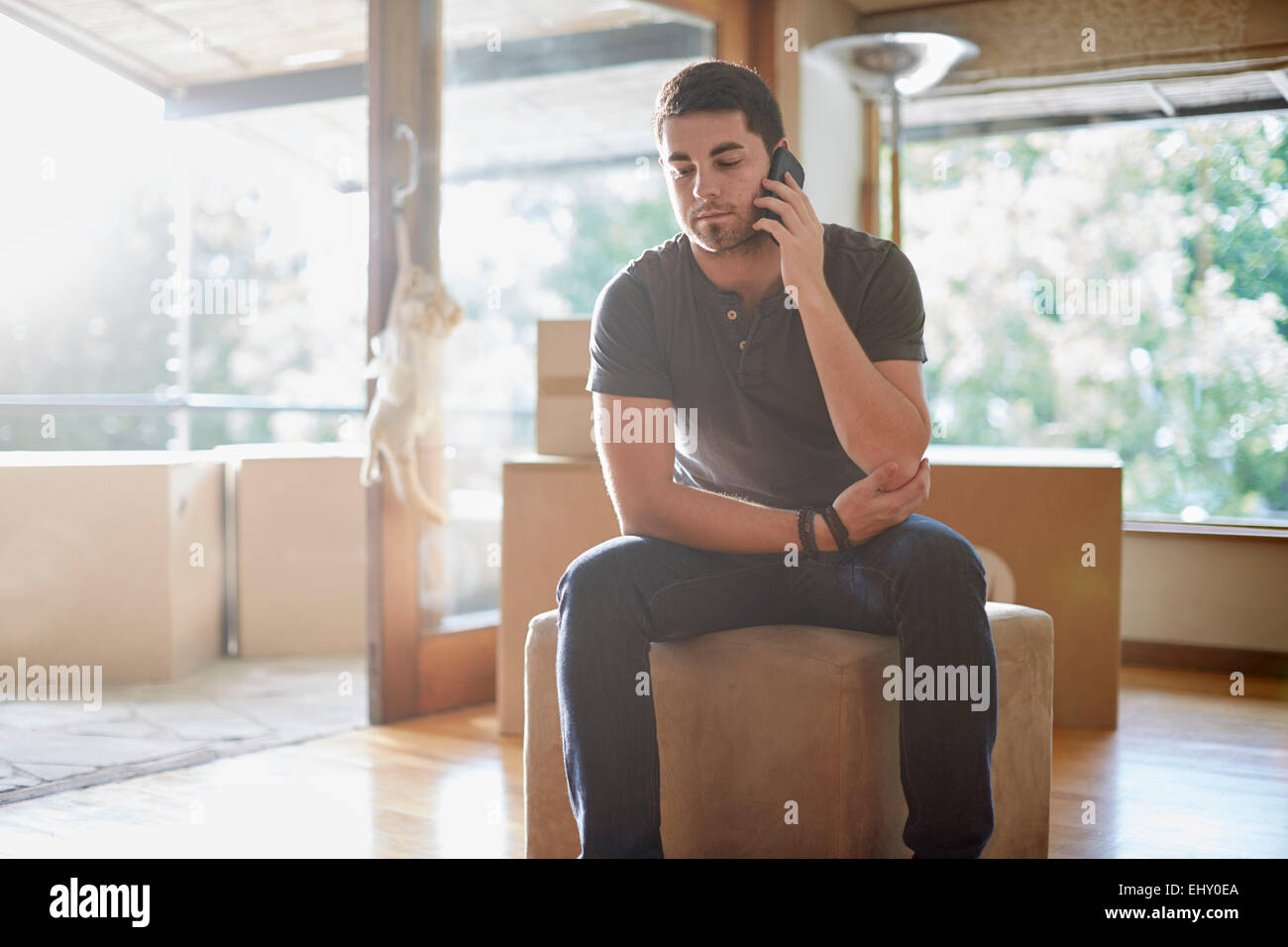 Man sitting on a box talking on his cell phone Stock Photo - Alamy