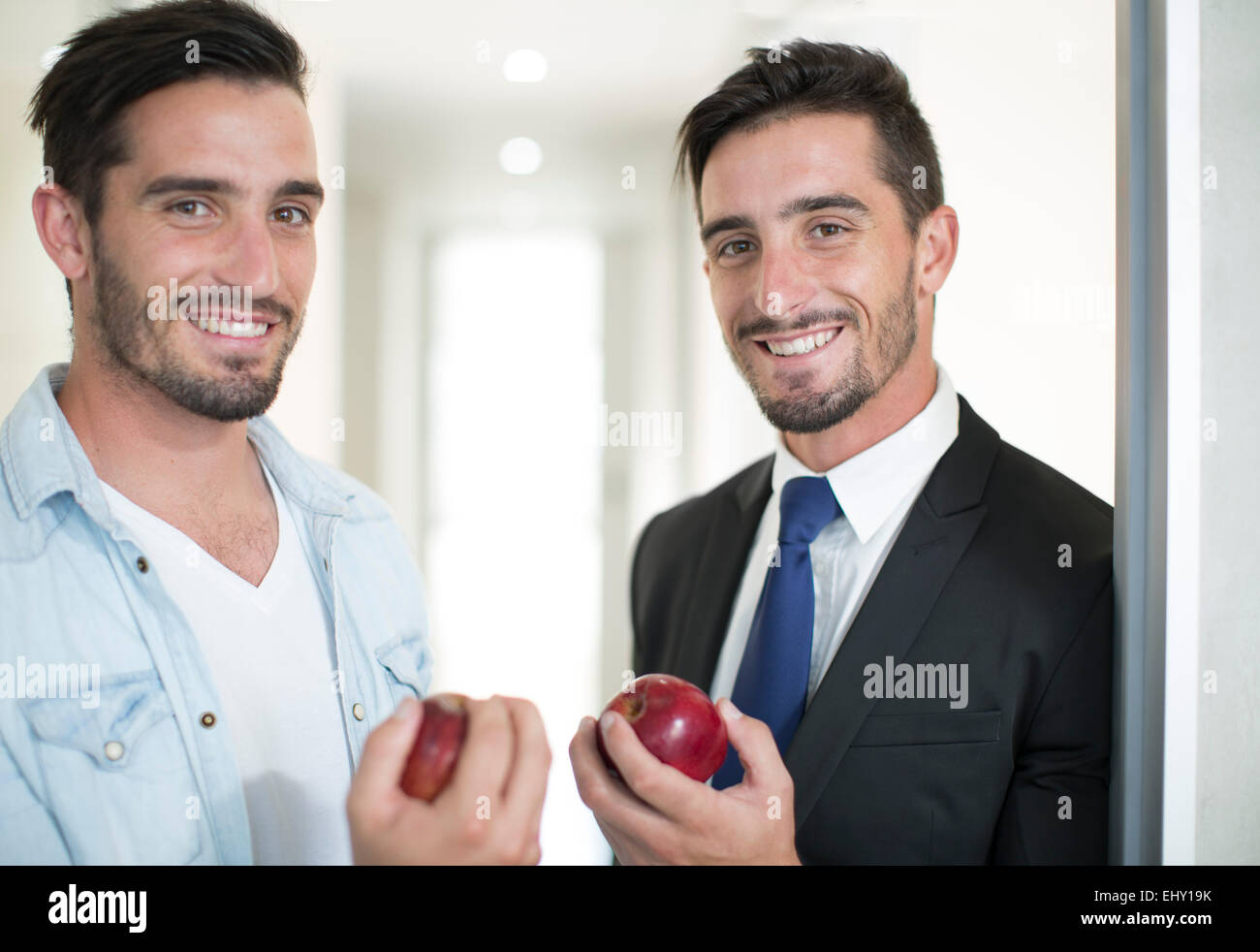Casually and formally dressed twin brothers holding apples Stock Photo ...