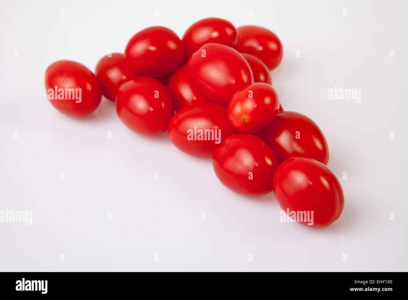 Handful of red shiny cherry tomatoes. Isolated over white background ...