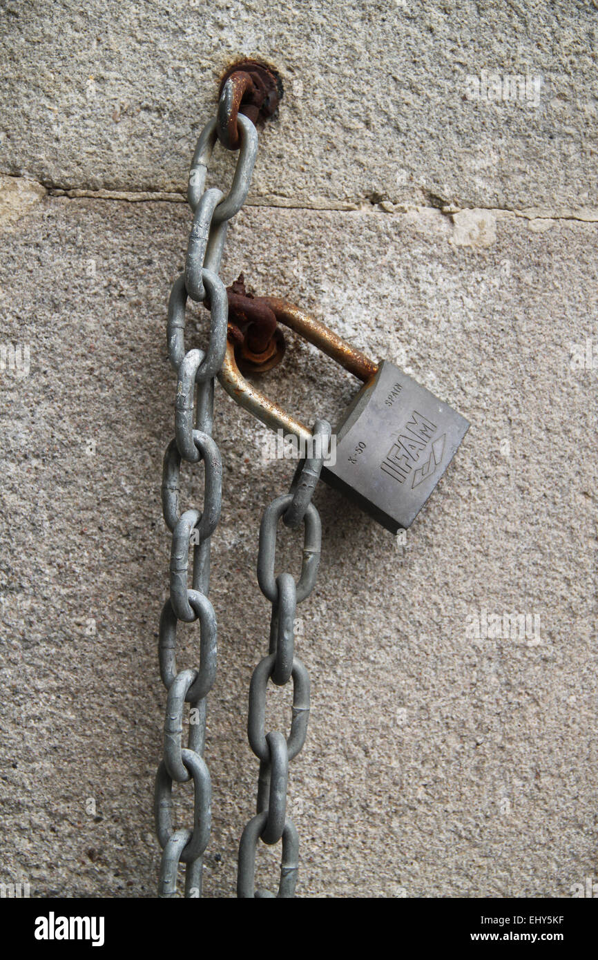 Metal Ifam padlock and chain attached to stone wall Stock Photo - Alamy