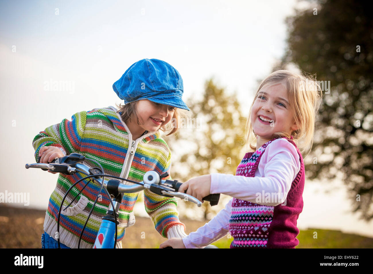 Two girls playing with bicycle Stock Photo - Alamy