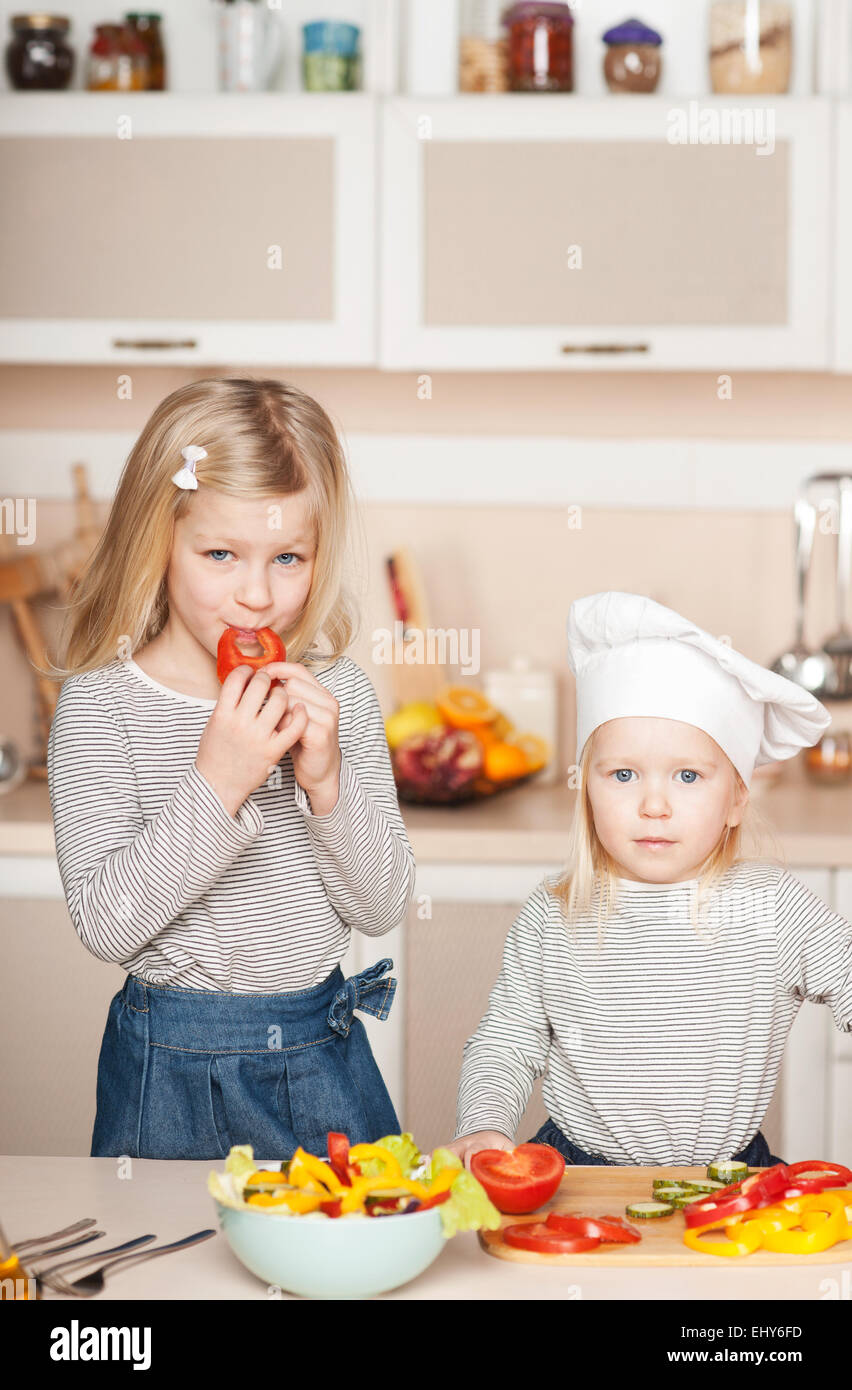 Cute girls trying to cook salad and help mother Stock Photo - Alamy