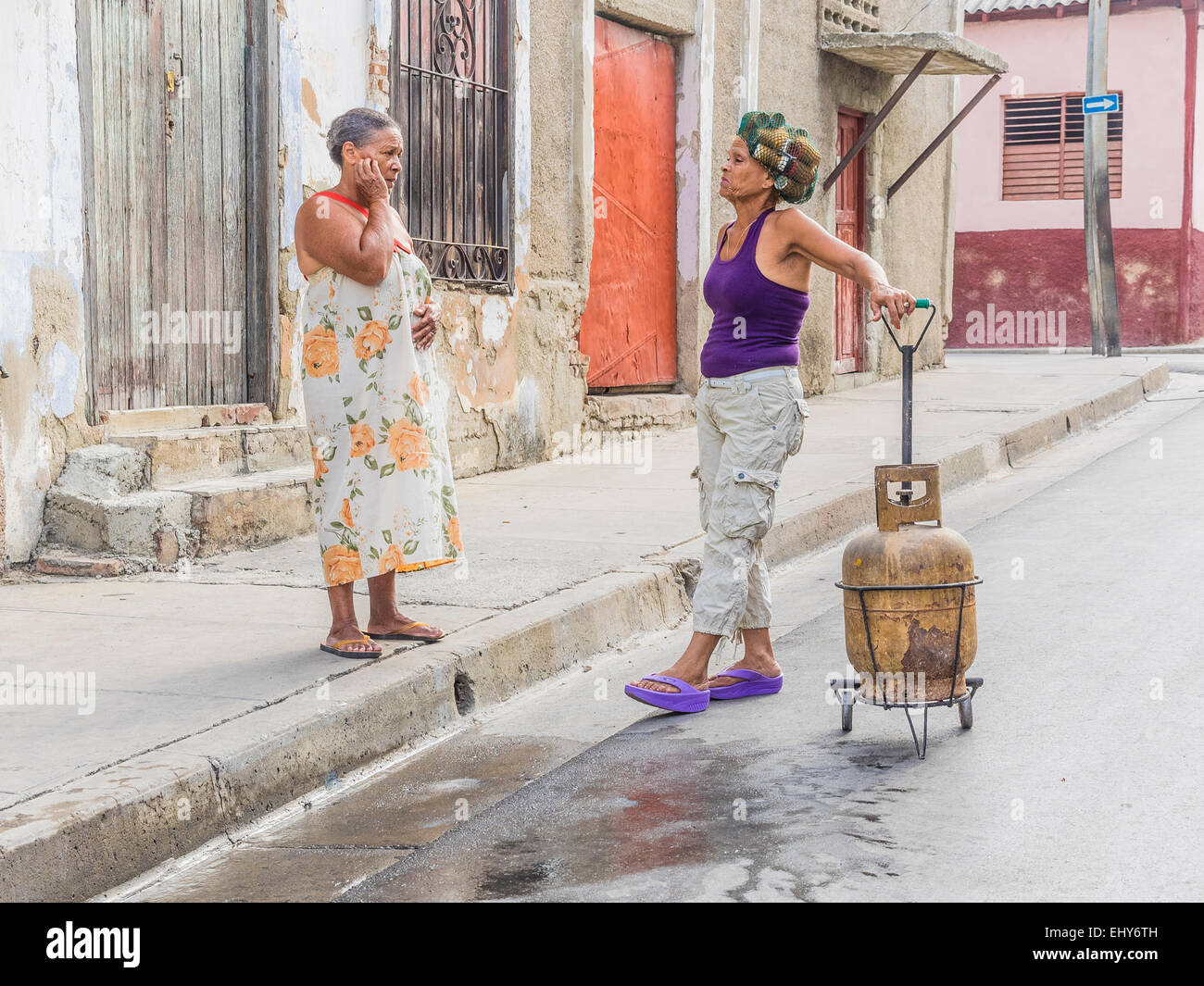 Two Hispanic women talking outside, one with hair curlers in her hair ...