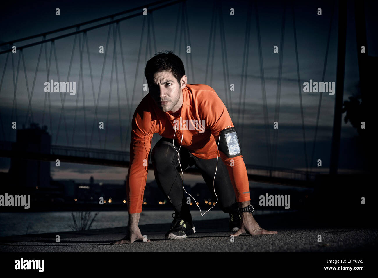 Male runner crouching to start at twilight Stock Photo - Alamy