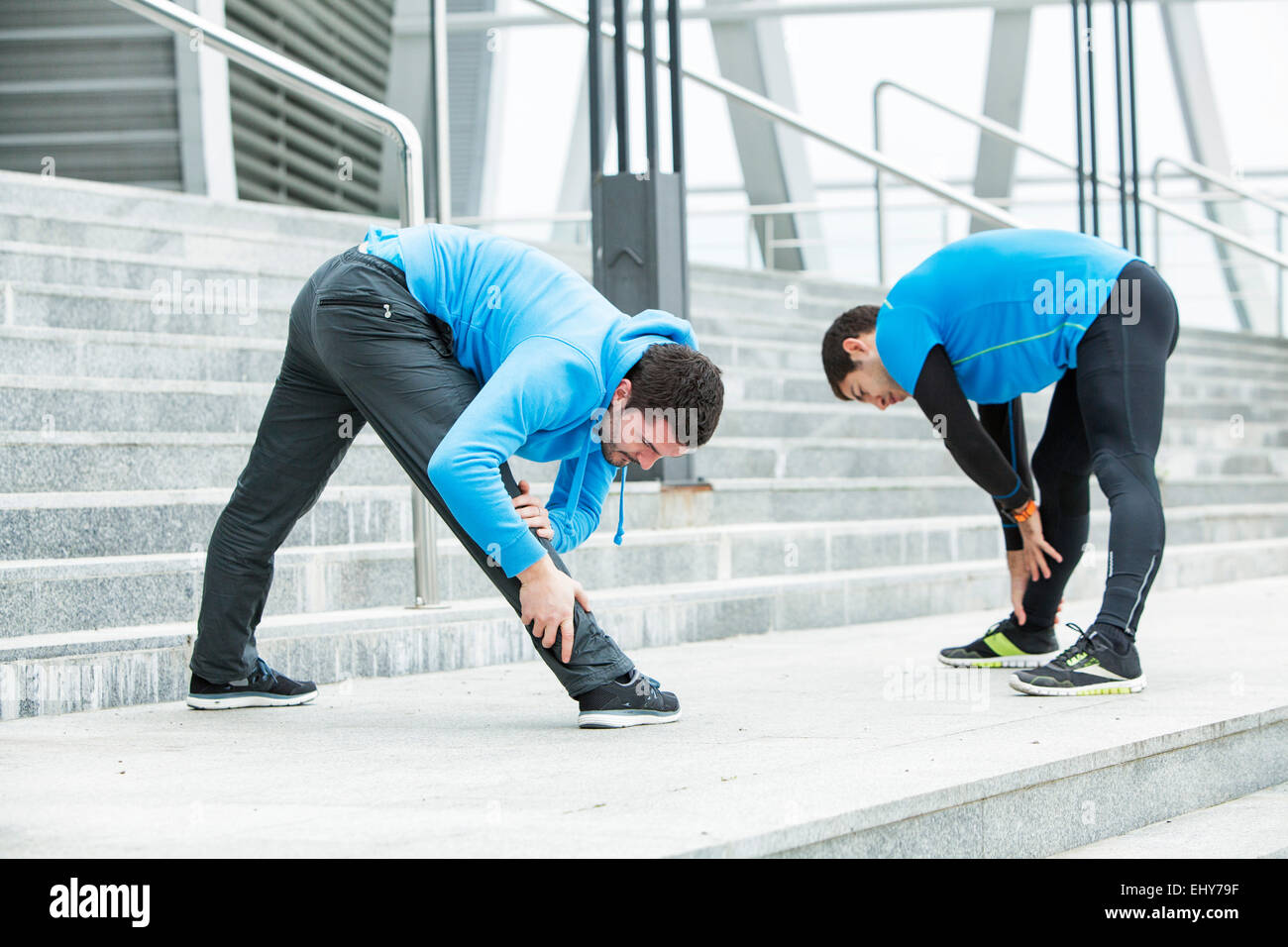 Male runners stretching and warming up together Stock Photo - Alamy