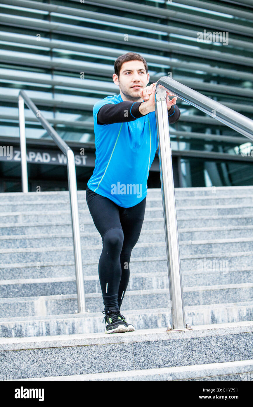 Male runner stretching and warming up in city Stock Photo - Alamy