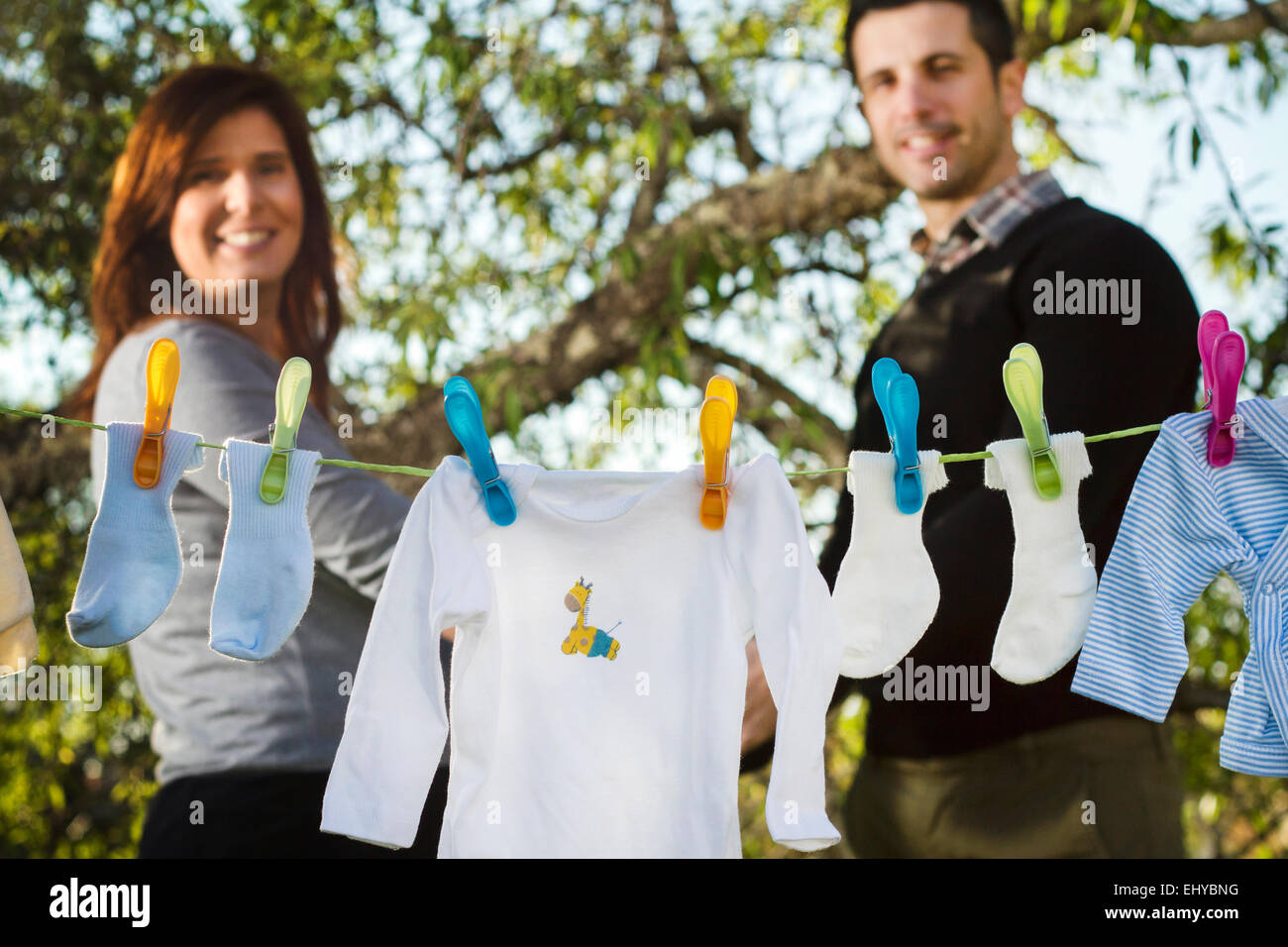 Close up view of a expecting pregnant happy next to baby clothes in a ...
