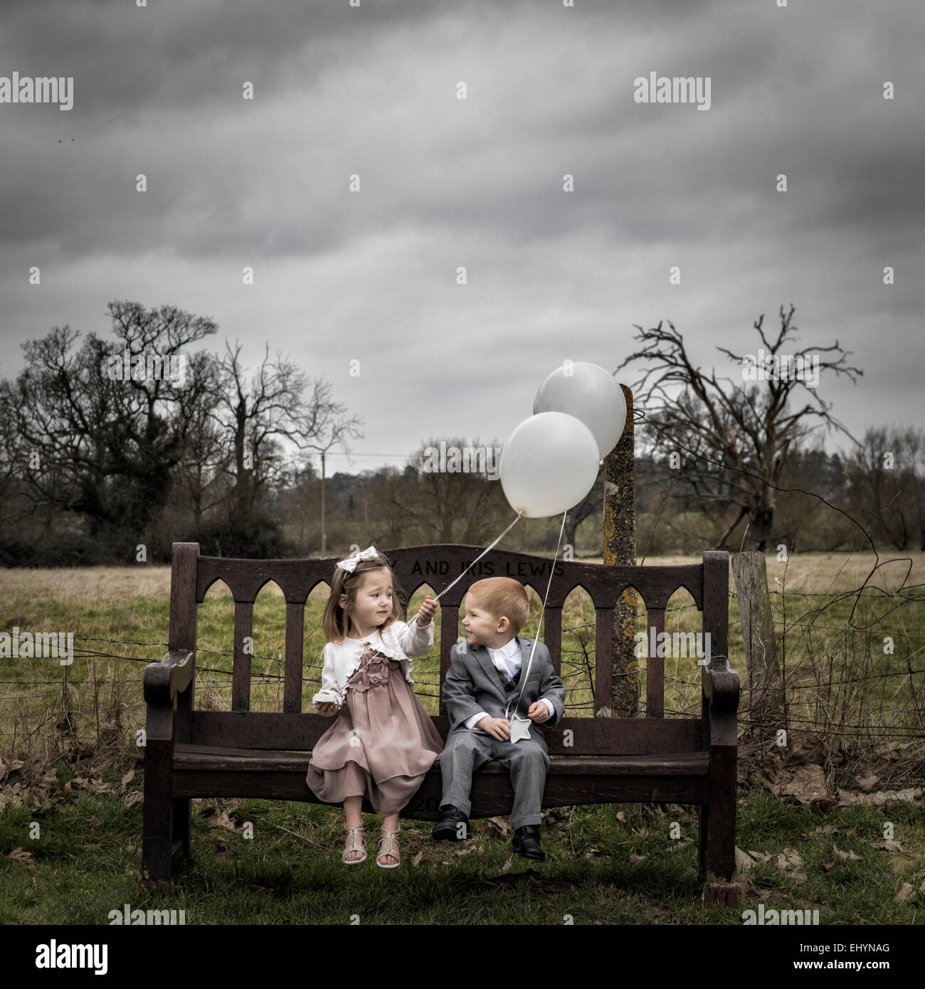 Girl and boy sitting on a bench with balloons Stock Photo - Alamy