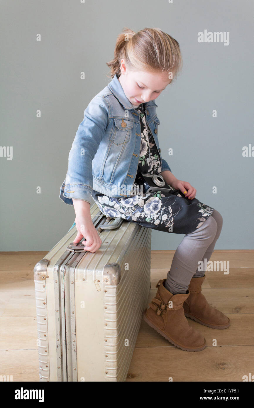Girl sitting on suitcase Stock Photo - Alamy