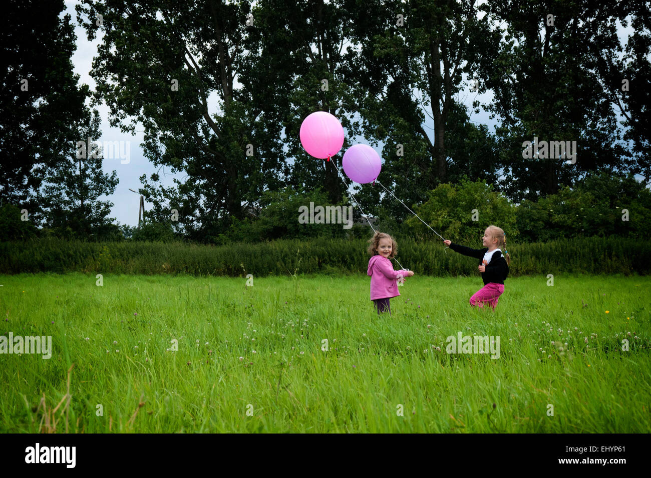 Two girls playing with balloons in a garden in summer, Poland Stock ...