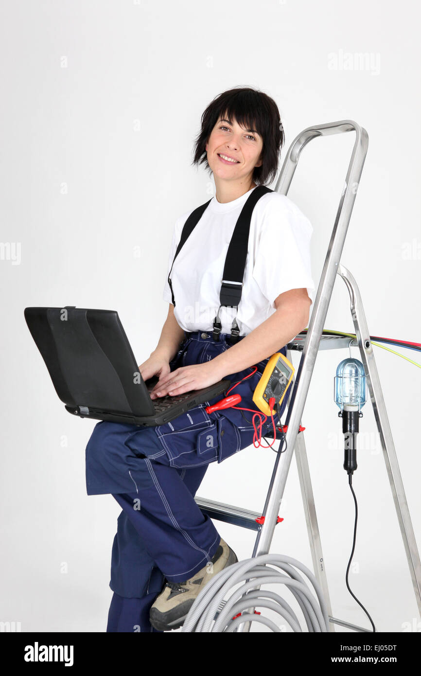 Female electrician sat on ladder with laptop Stock Photo - Alamy