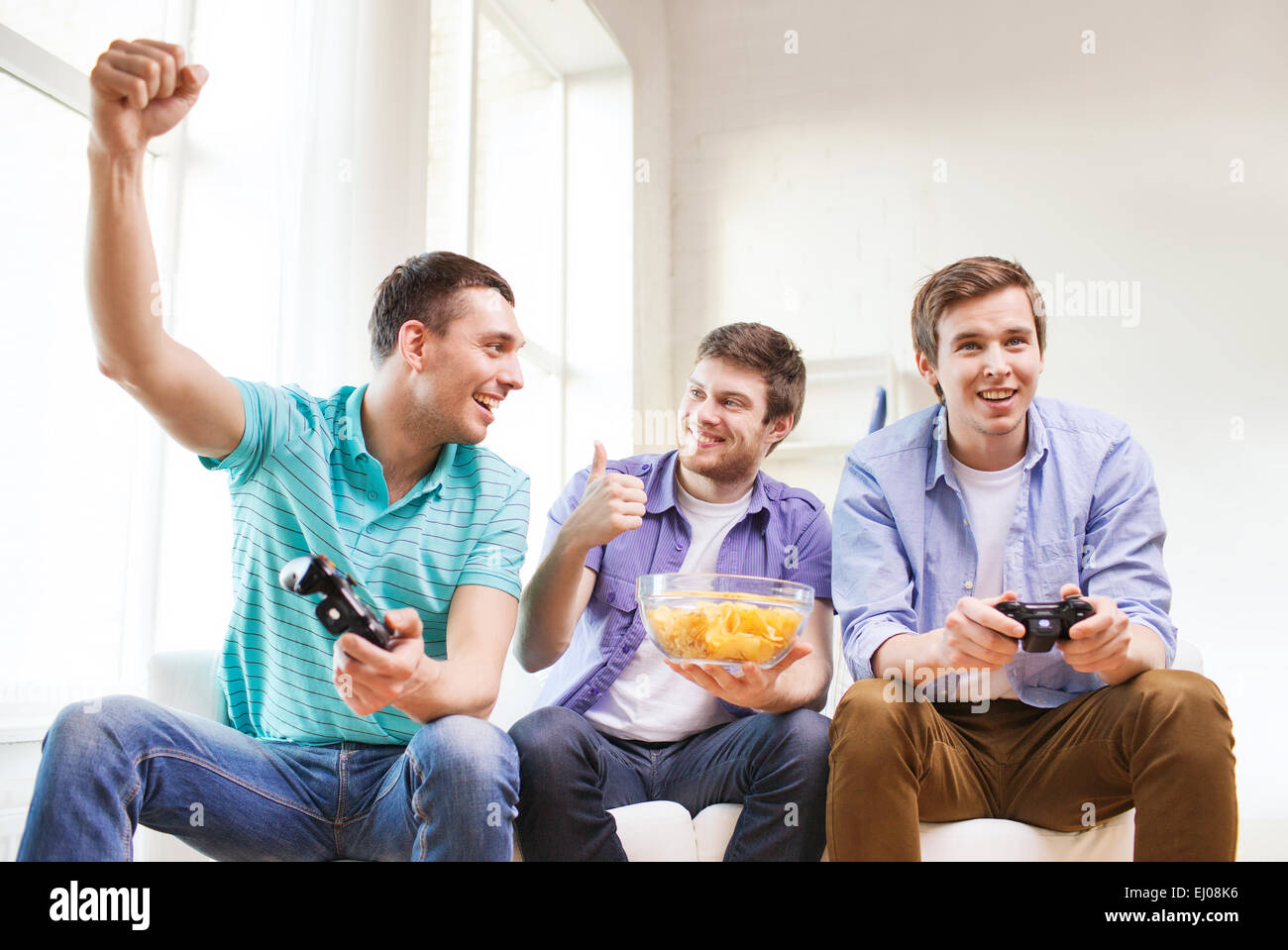 smiling friends playing video games at home Stock Photo - Alamy