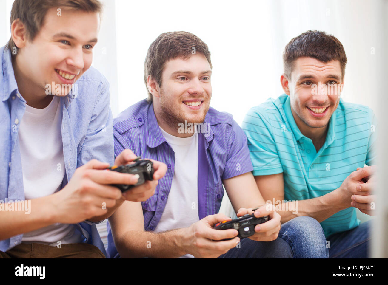 smiling friends playing video games at home Stock Photo - Alamy