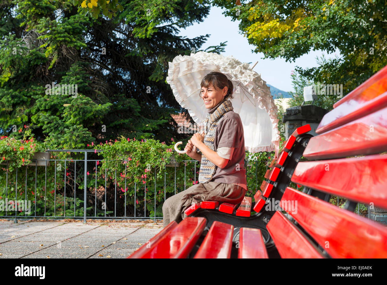 Woman with an umbrella sitting on a bench in Ticino, Switzerland Stock ...