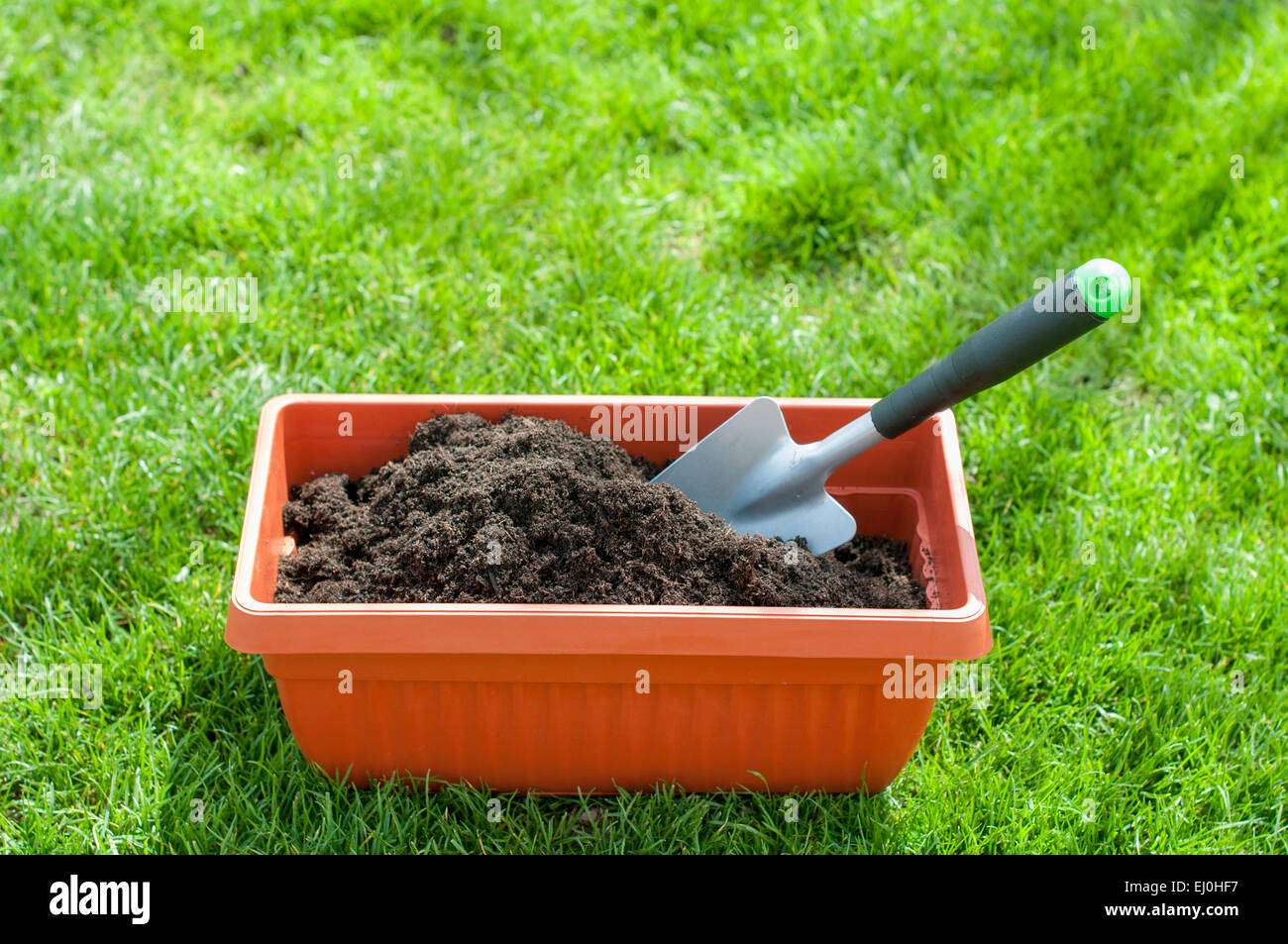 Brown pot with garden shovel and compost Stock Photo - Alamy