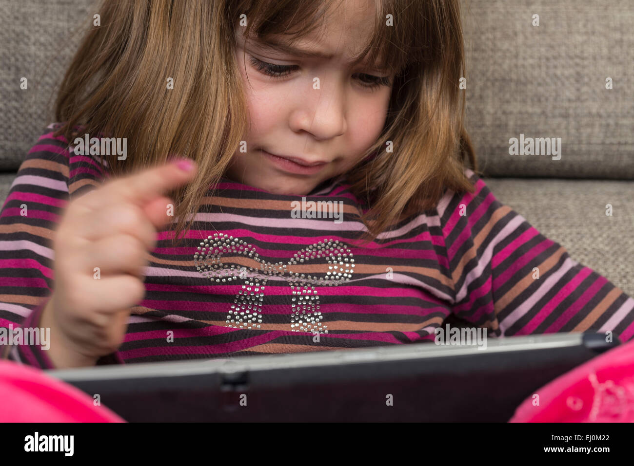 Little girl using tablet digital on the sofa Stock Photo - Alamy