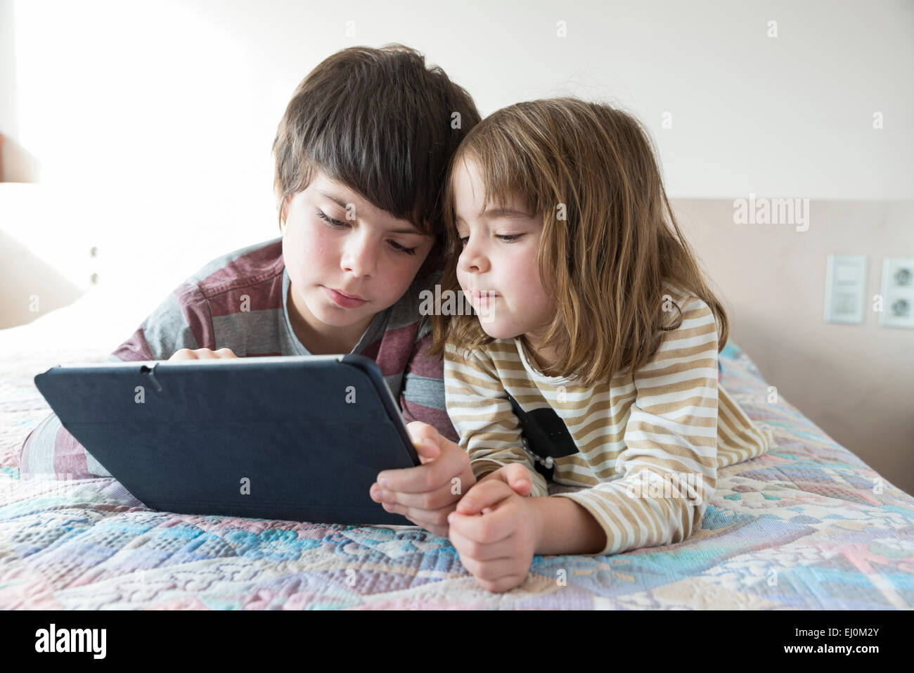 Children playing with a digital tablet on the bed Stock Photo - Alamy