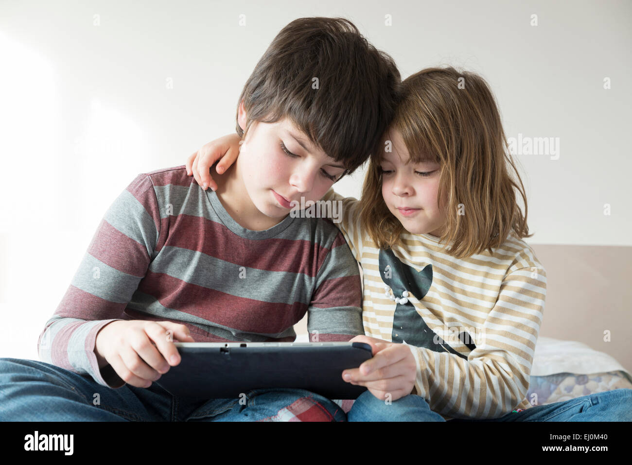 Children playing with a digital tablet on the bed Stock Photo - Alamy