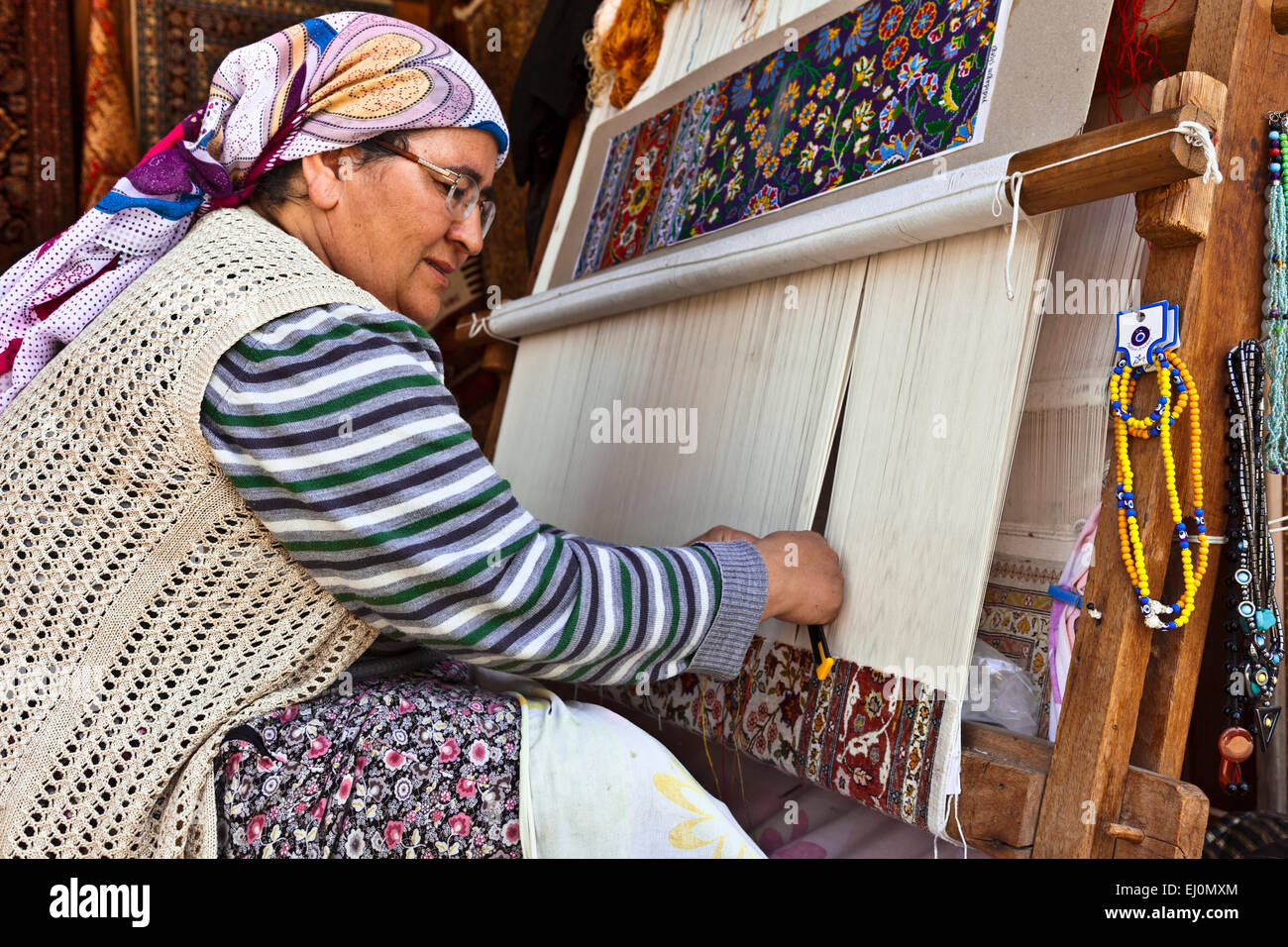 Unidentified female weaver knotting a handmade carpet at the shopping ...