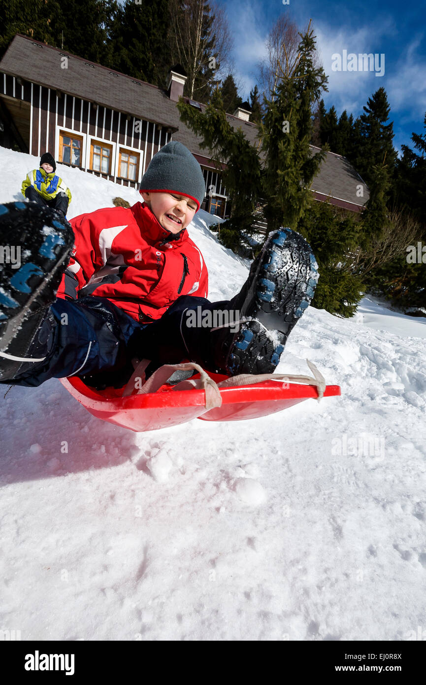 boys riding snow plastic sled in wintertime Stock Photo - Alamy