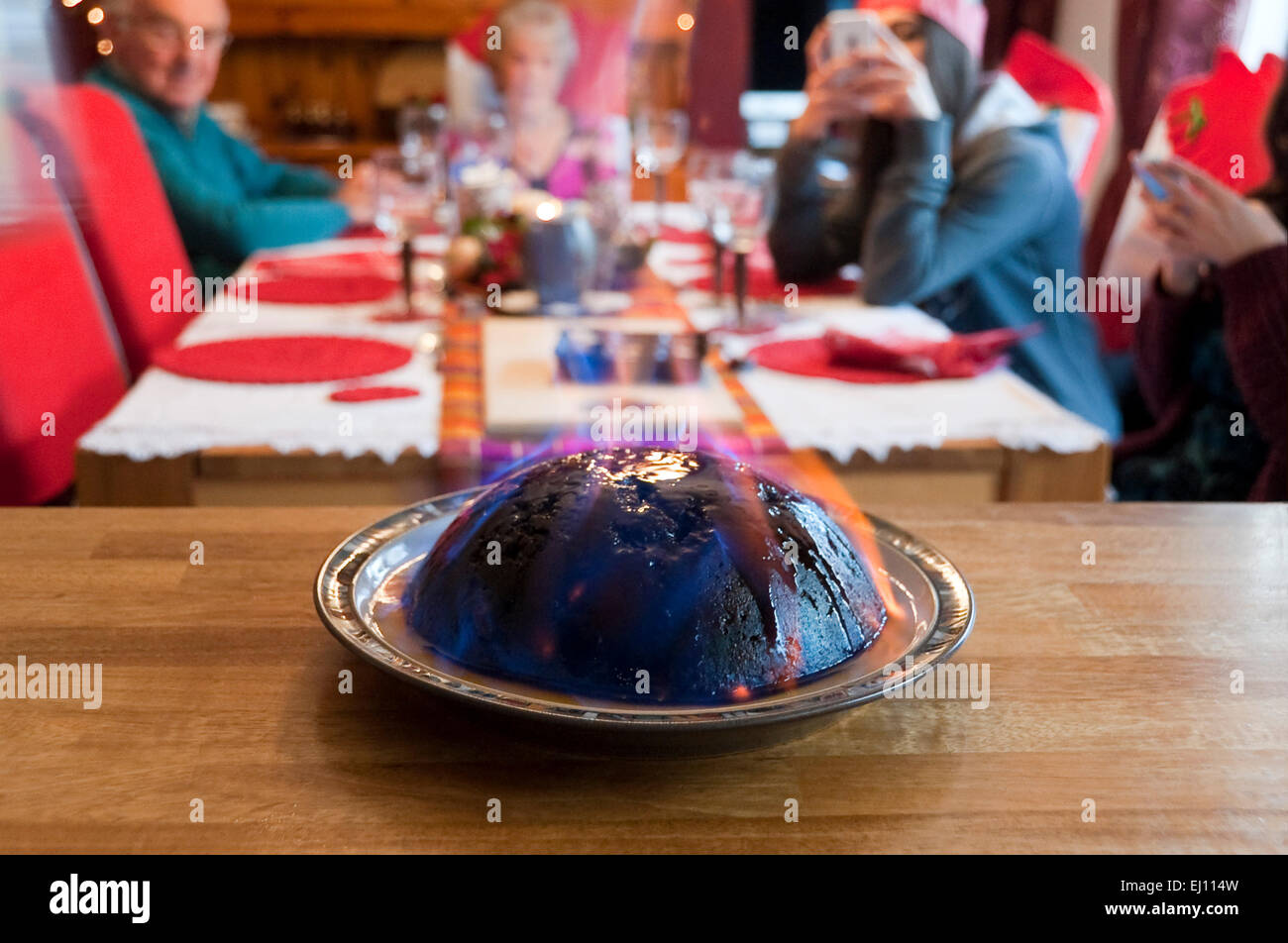 Horizontal view of a Christmas pudding alight during a family Christmas ...
