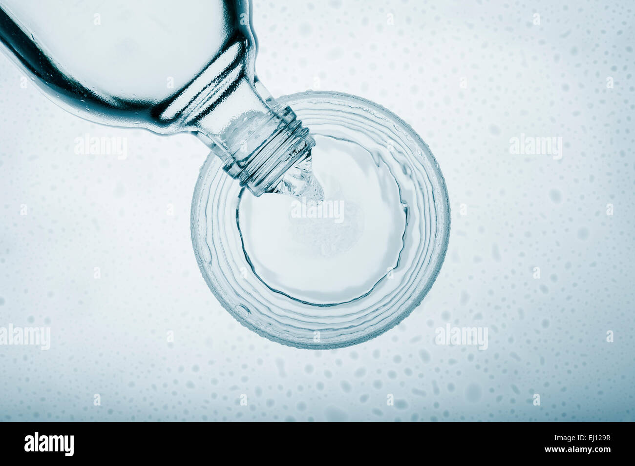 pouring water into glass from a bottle, view from above on blue ...