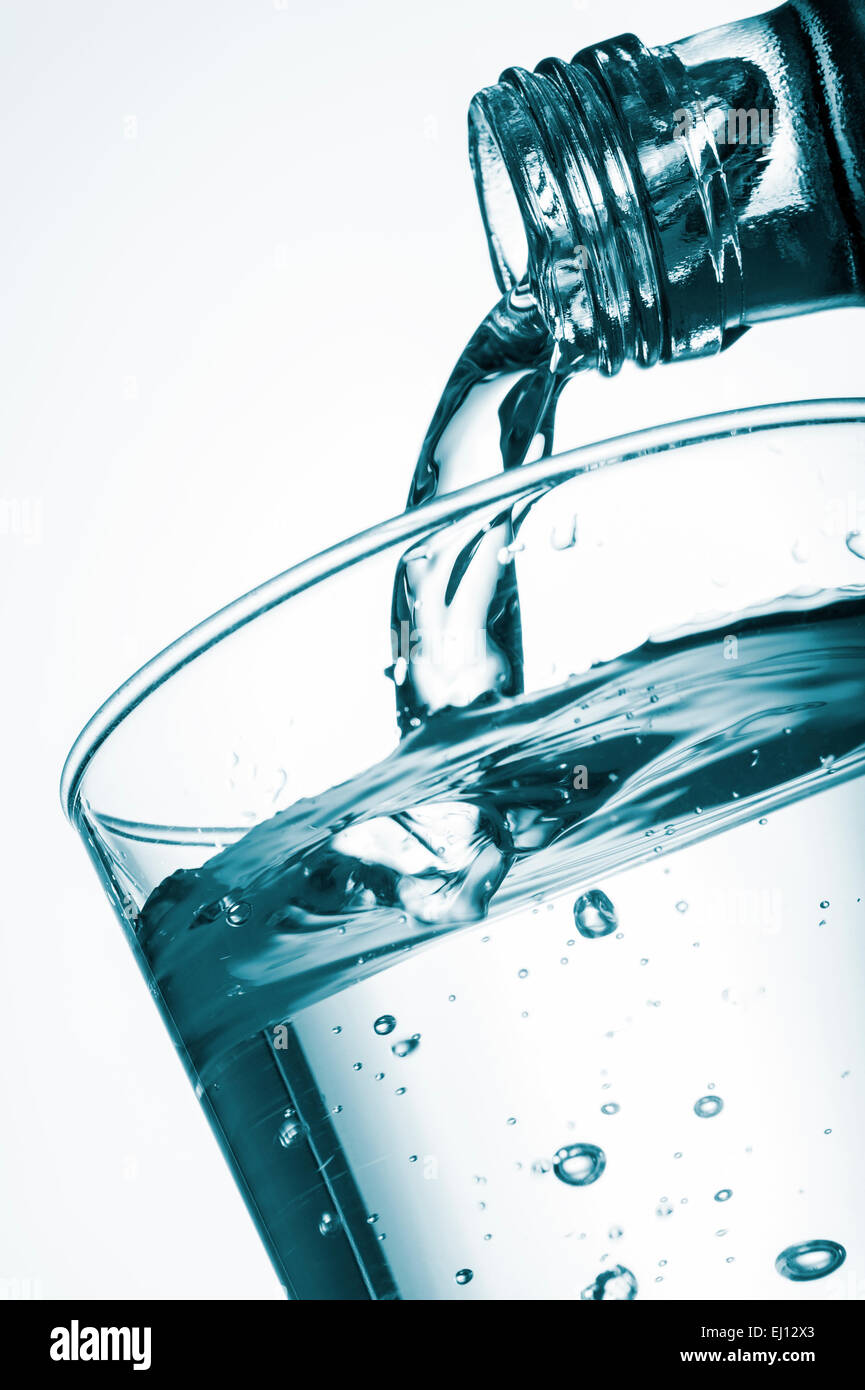 pouring water into glass from a bottle, on white background Stock Photo - Alamy